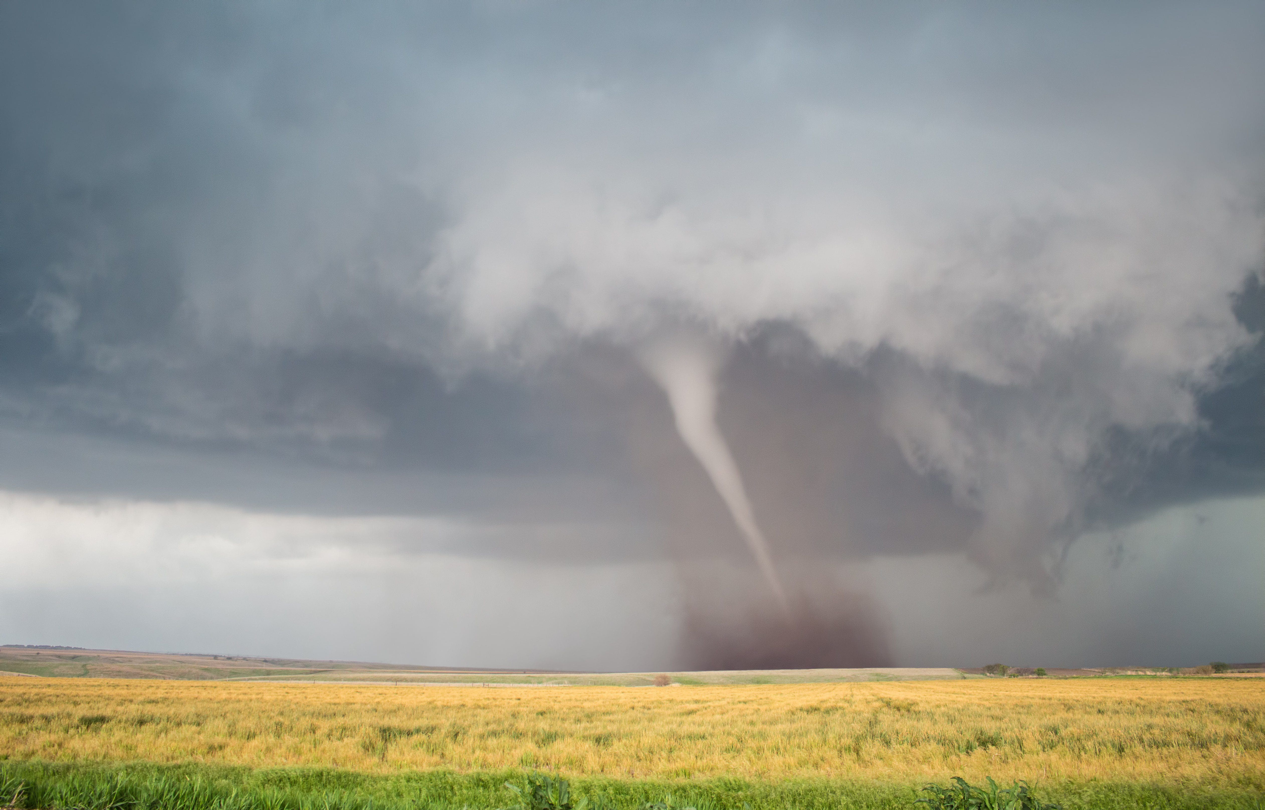 A thin cone tornado spins over the open landscape of the Great Plains – City of College Station